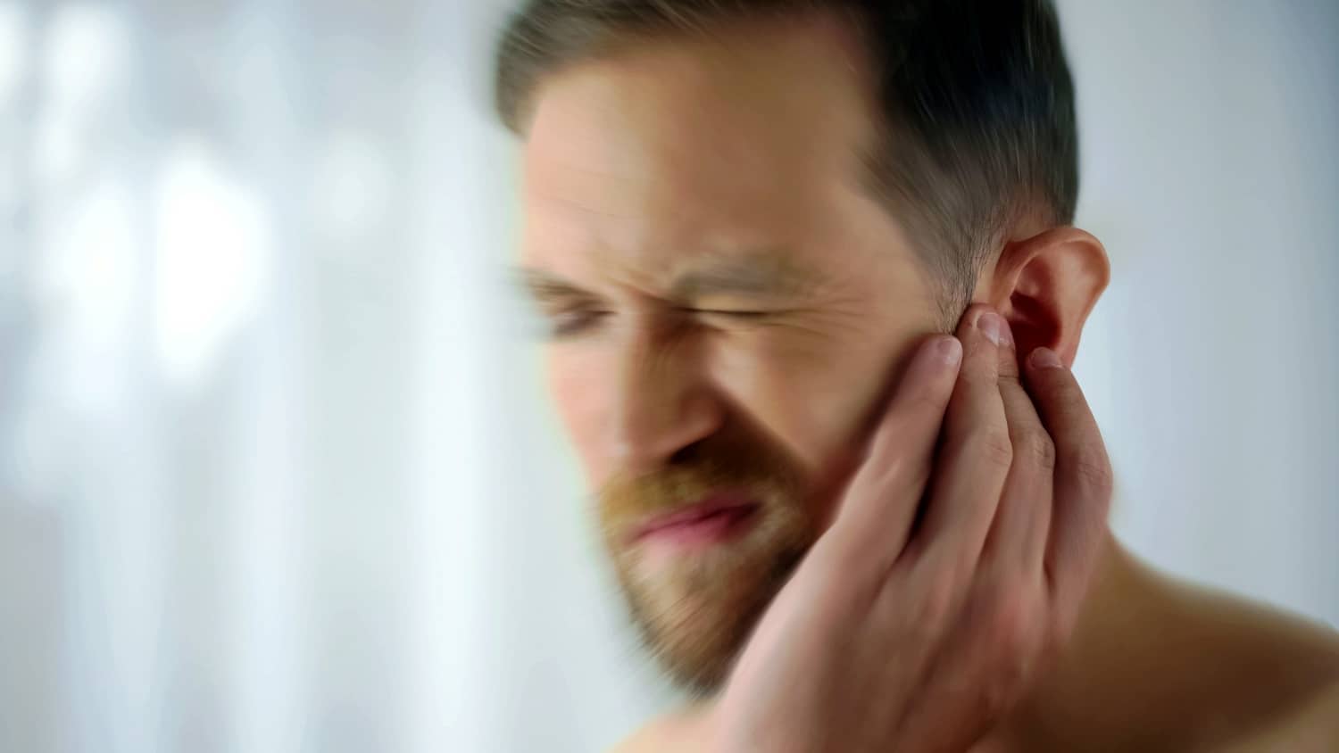 Man with hand over ear - Professional Audiological Services